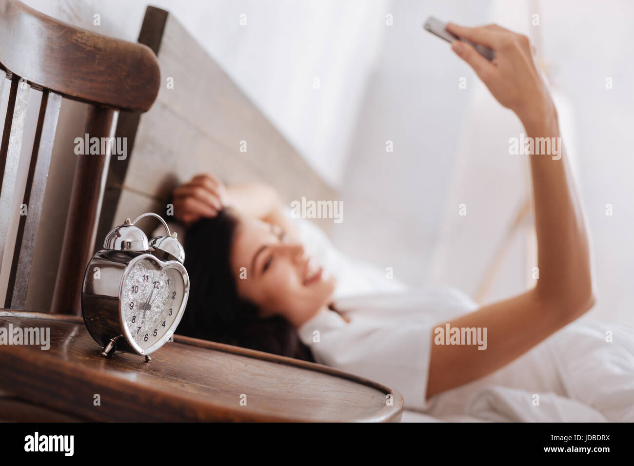 Silver heart shaped alarm clock with woman taking selfie behind Stock ...