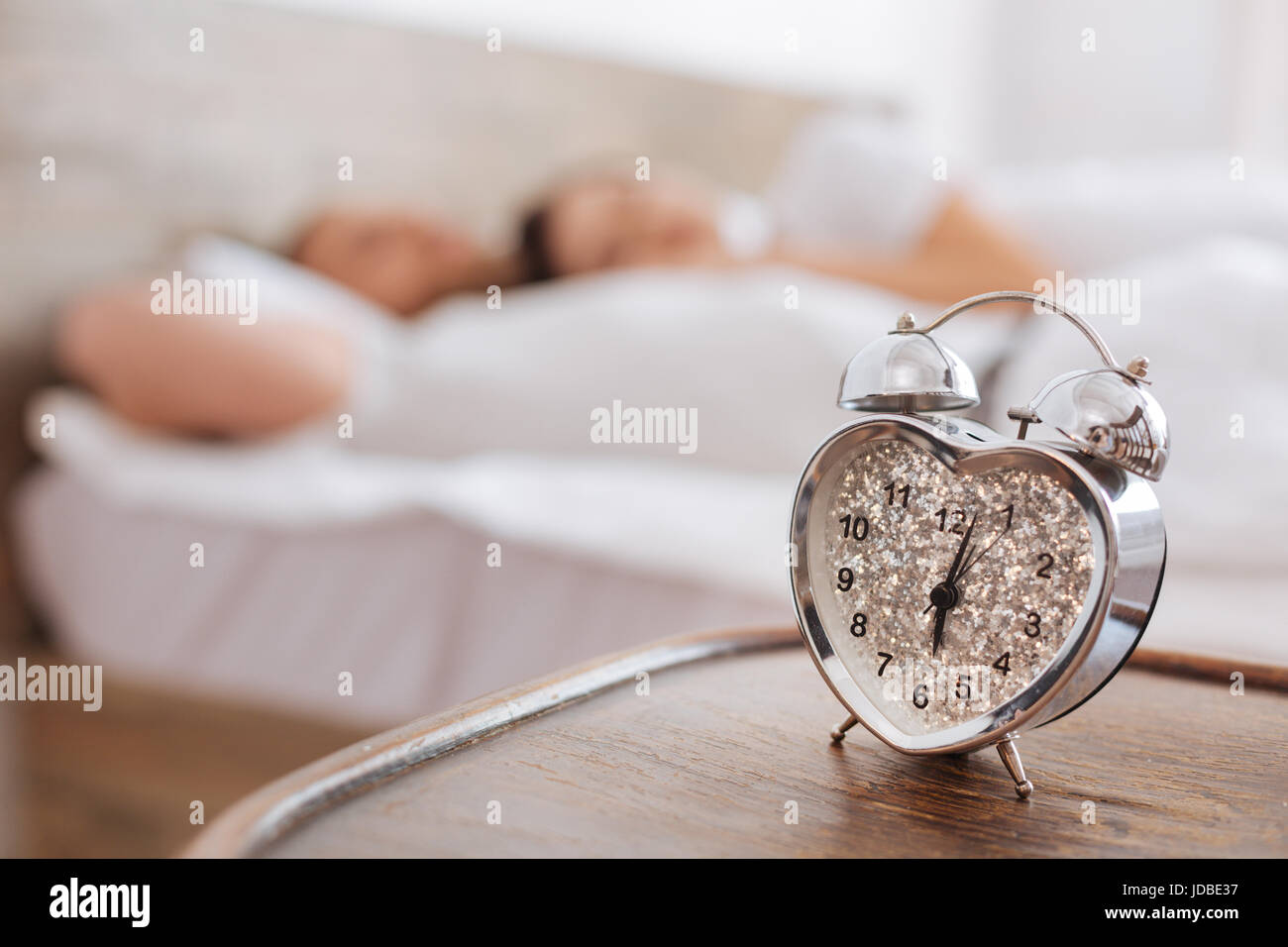 Selective focus on alarm clock with couple sleeping behind Stock Photo ...