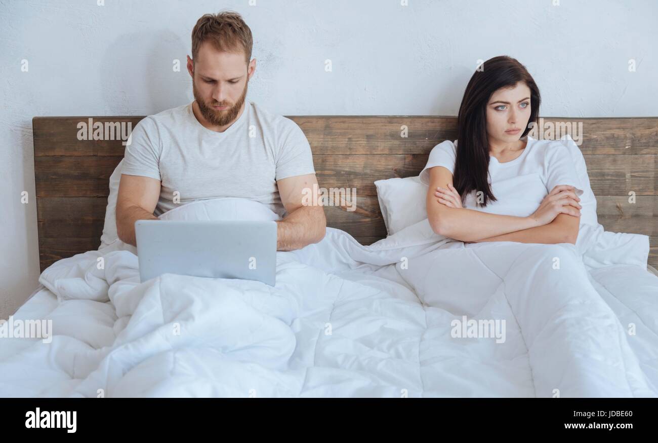 Couple ignoring each other in bed Stock Photo - Alamy