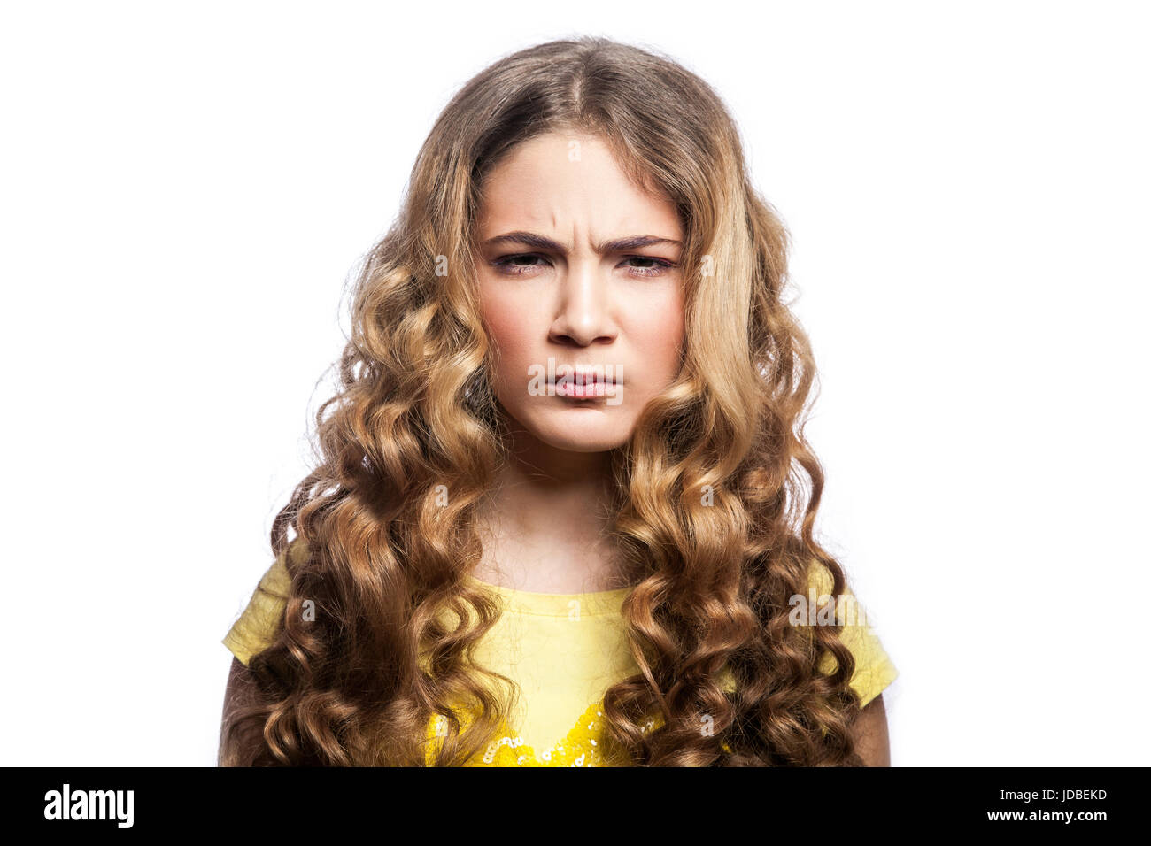 Portrait of unhappy angry girl with wavy hairstyle and yellow t shirt ...