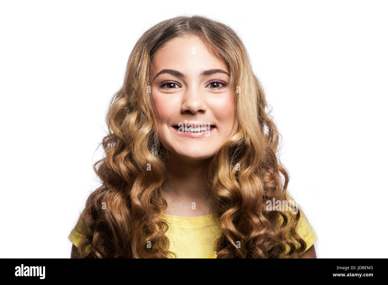 Portrait of happy toothy smiley girl with wavy hairstyle and yellow t ...
