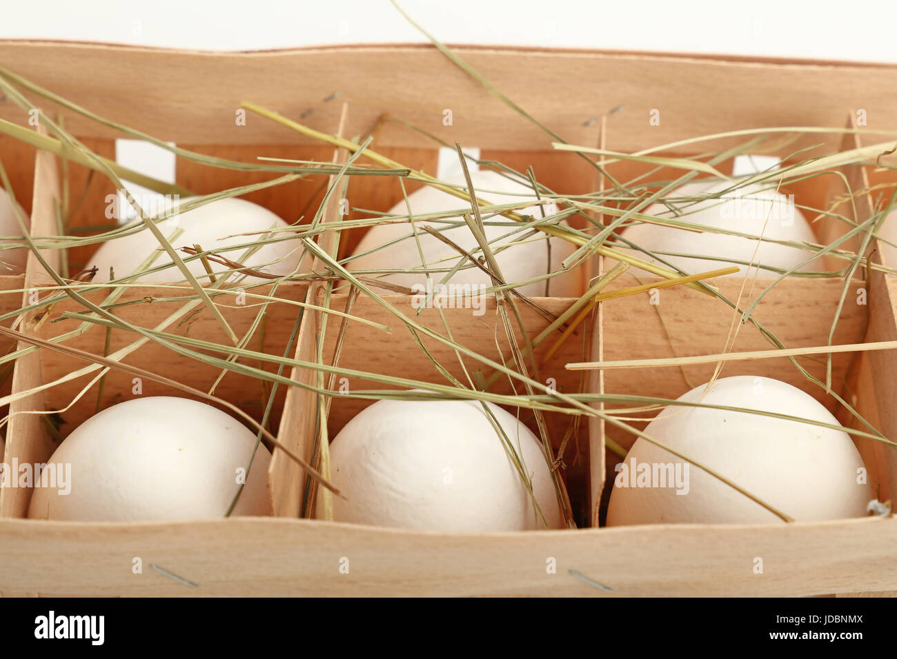Six fresh farm chicken eggs in wooden container box with hay on white ...