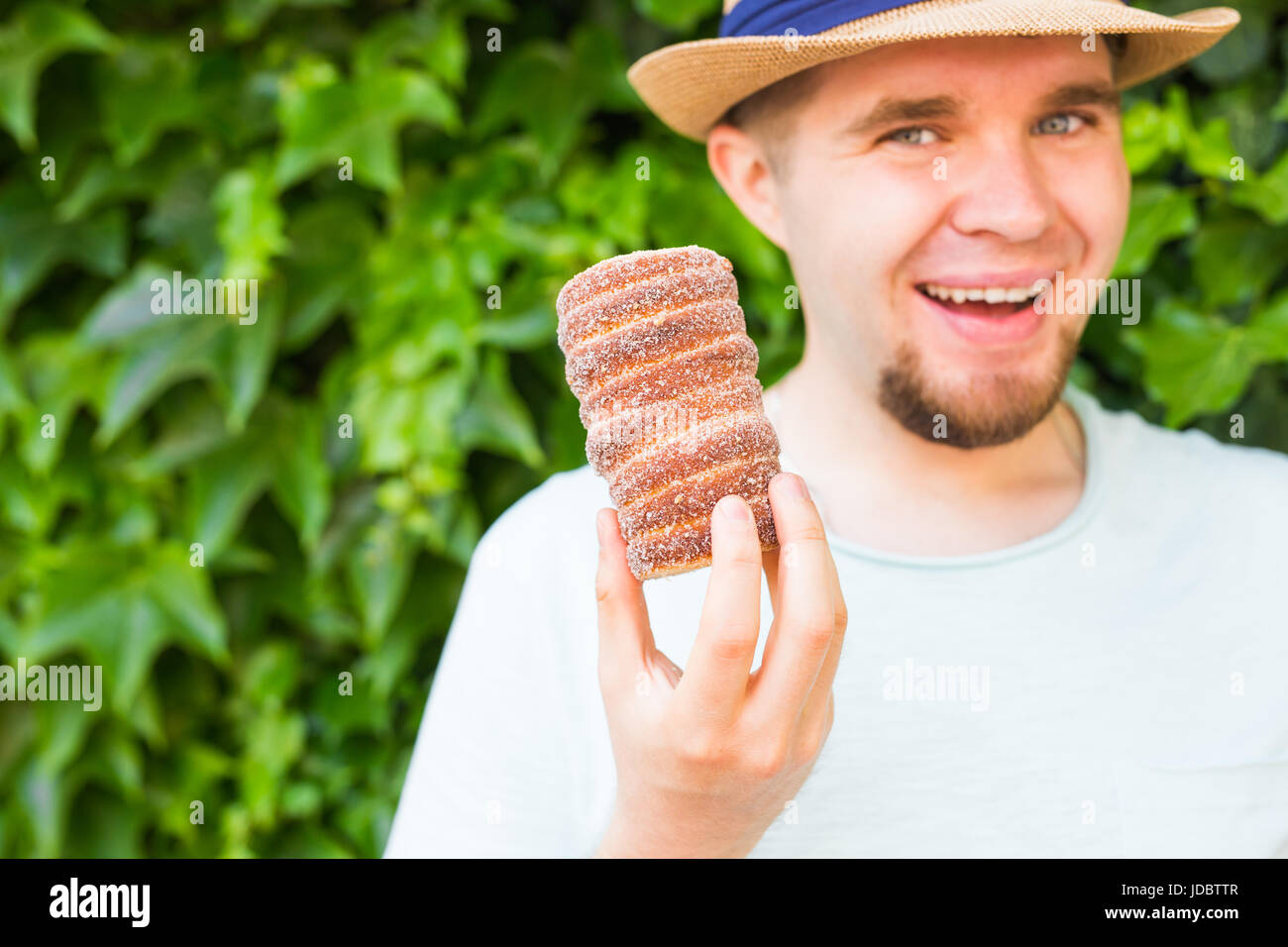 Happy man tourist holds in hand Trdlo or Trdelnik background. Fresh ...