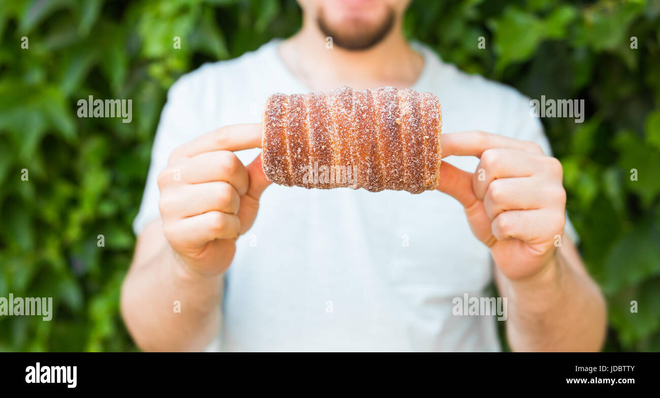 Close-up of tourist holds in hand Trdlo or Trdelnik background. Fresh ...