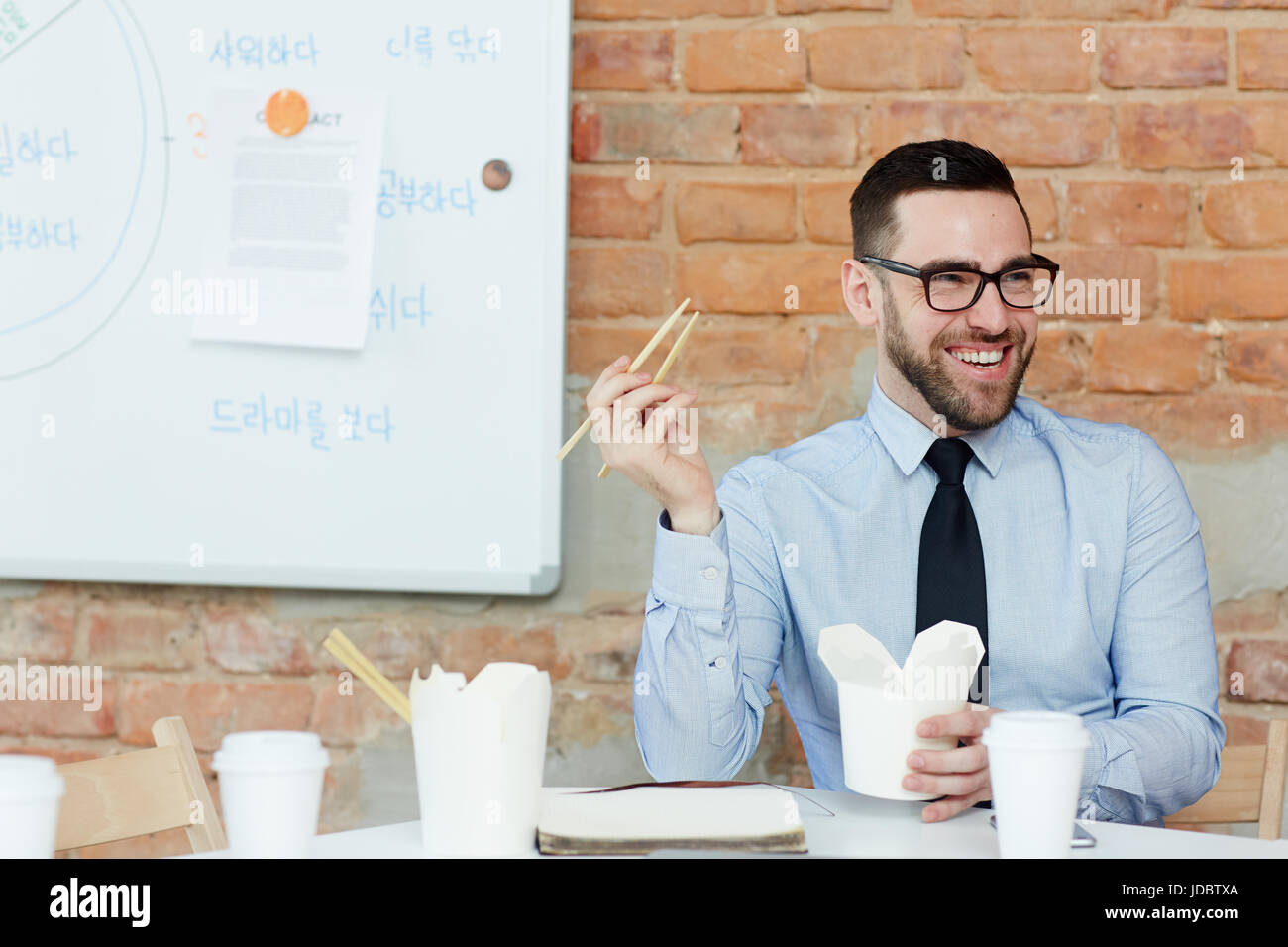 Happy trader with chopsticks eating take-away food from box Stock Photo ...