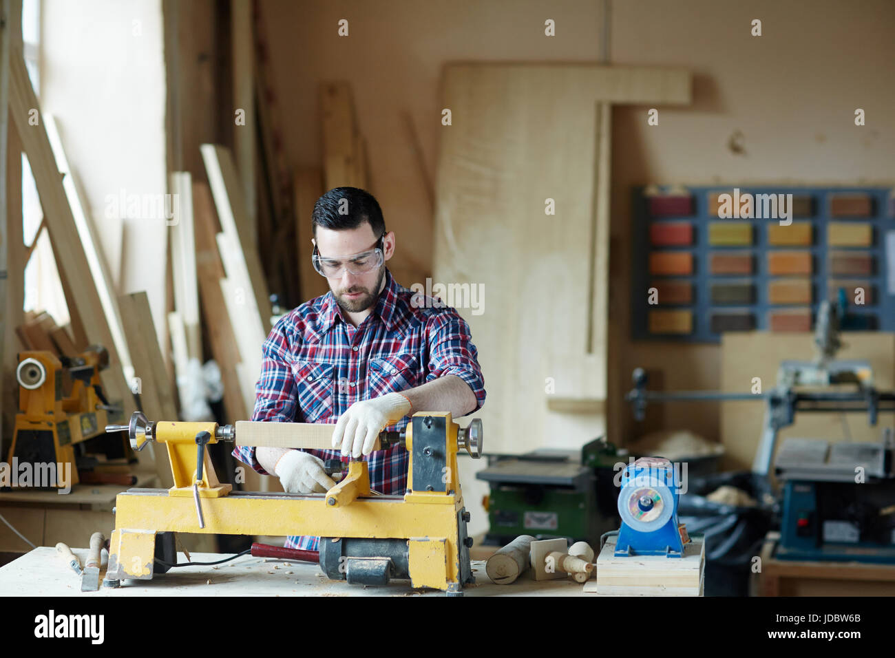 Man in gloves and protective eyeglasses woodworking in workroom Stock ...