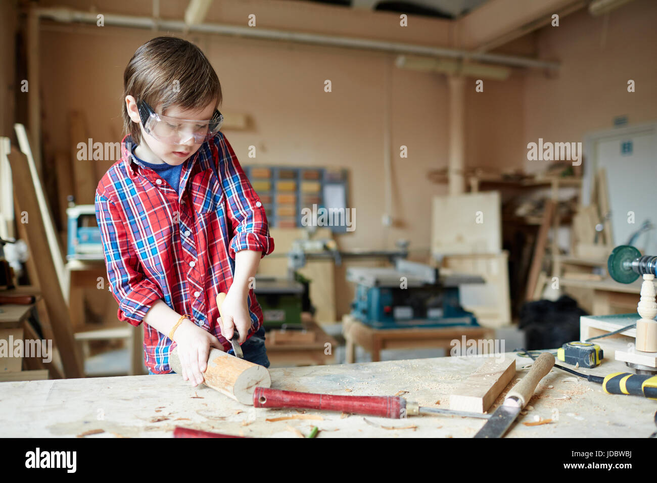 Boy with wood-chisel carving wooden plank Stock Photo - Alamy