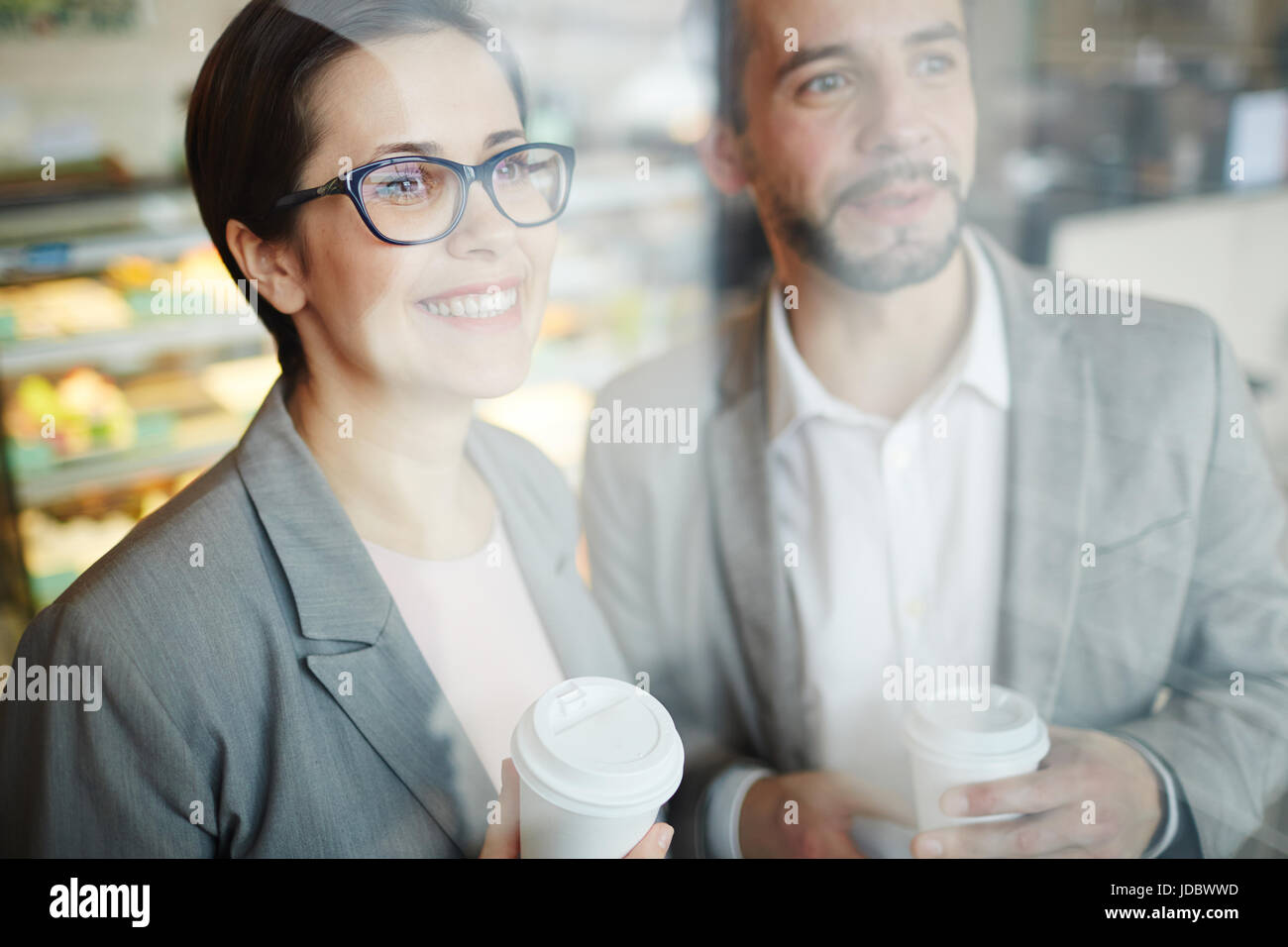 Portrait of two smiling business customers looking away and smiling in ...
