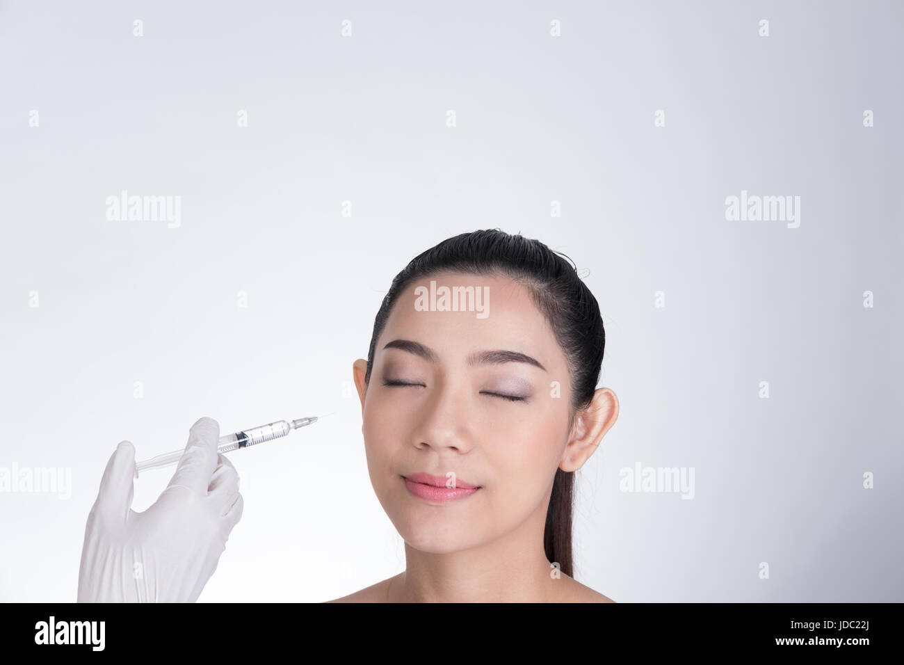 Doctor's hand making a botox injection in girl's face. young asian ...