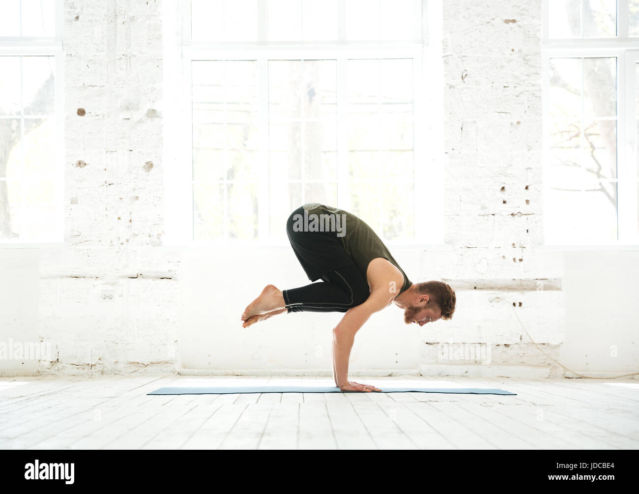 Side view of a man practicing advanced yoga indoors Stock Photo - Alamy