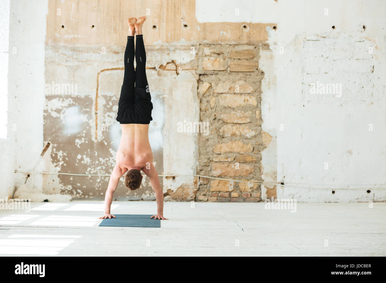 Full length back view of a man practising yoga poses indoors Stock ...