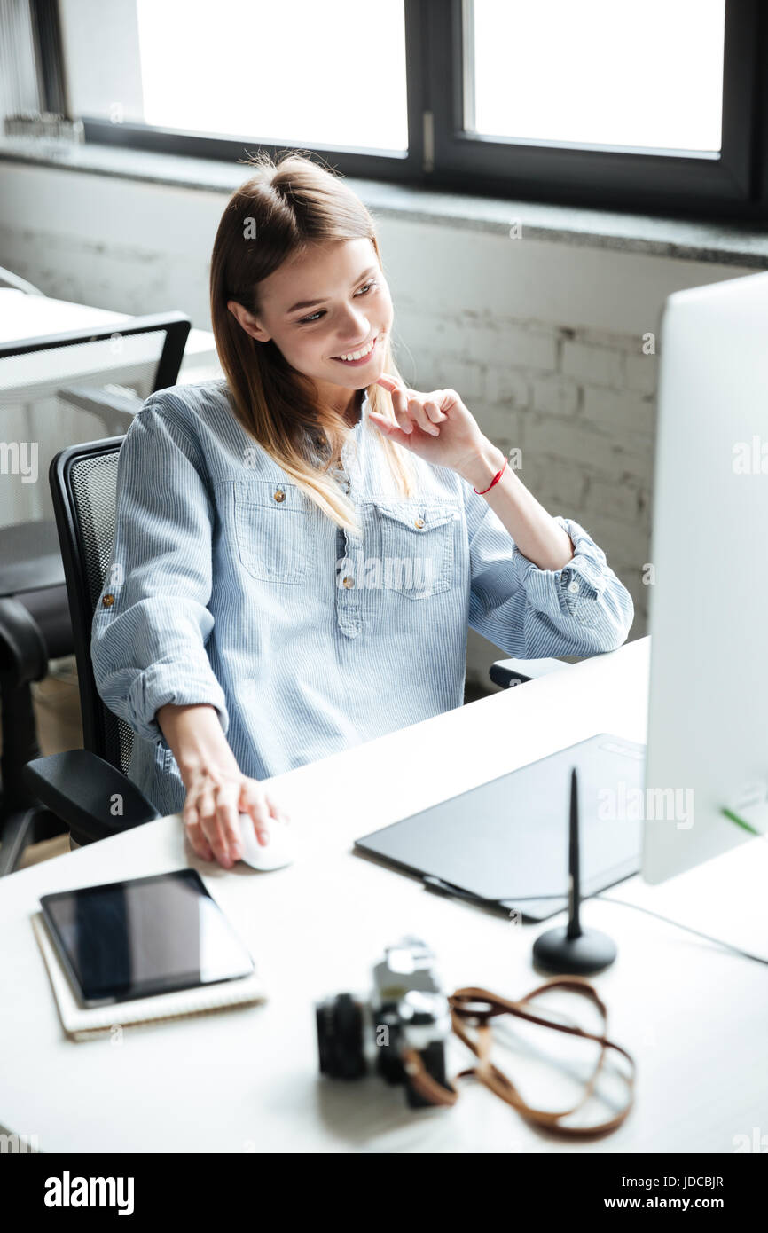 Picture of happy young woman work in office using computer. Looking ...