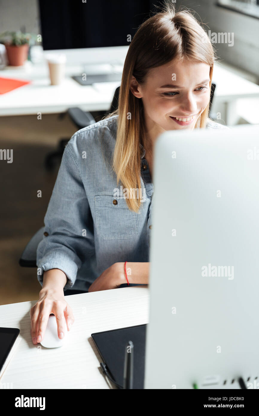 Picture of happy young woman work in office using computer. Looking ...