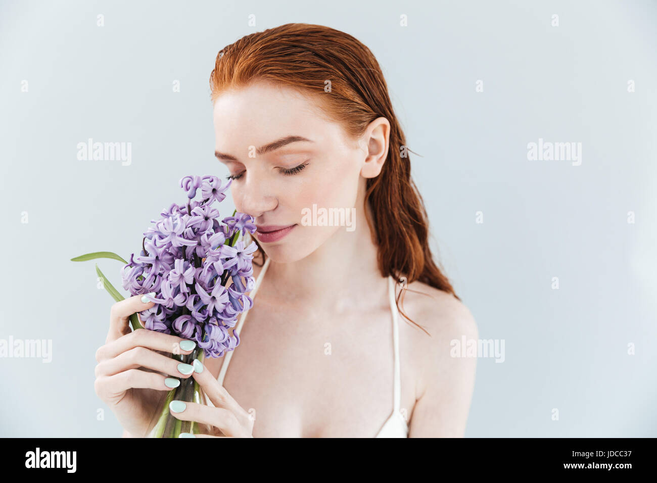 Close up portrait of a young ginger woman smelling hyacinth flowers ...