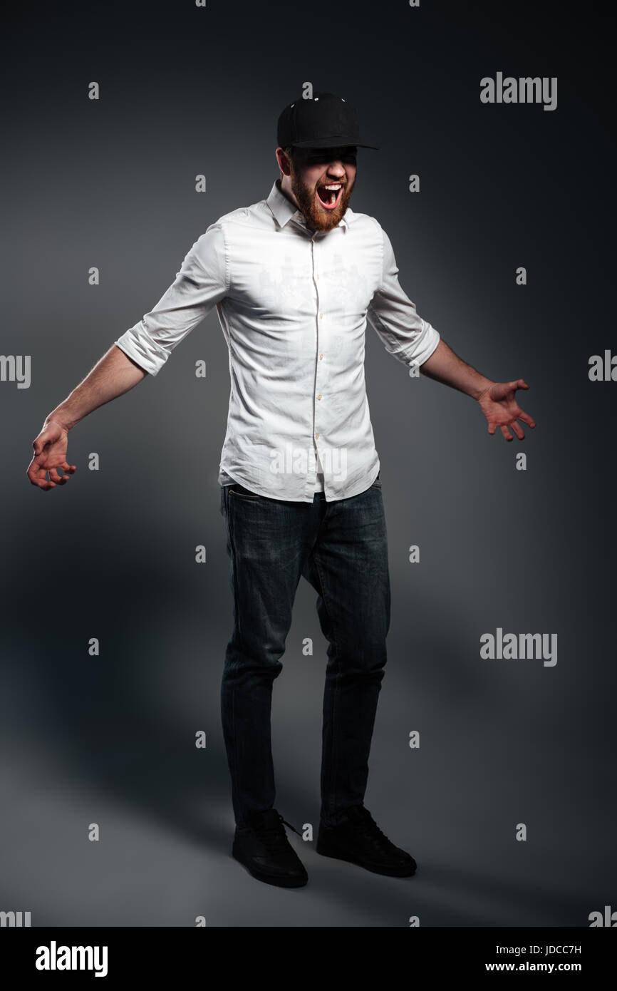 Image of screaming angry bearded young man wearing cap standing ...