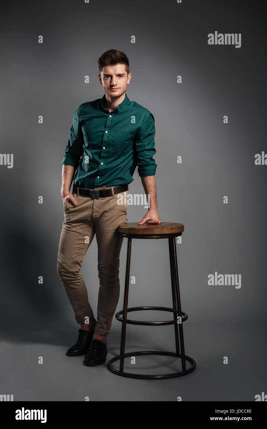 Picture of serious young man standing isolated over grey background ...