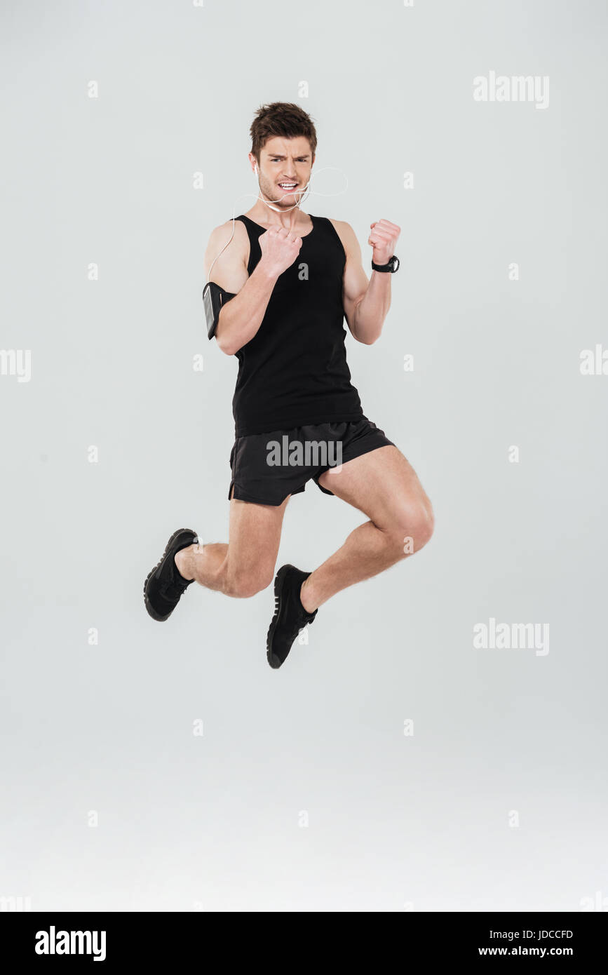 Picture of handsome young sportsman jumping showing winner gesture ...