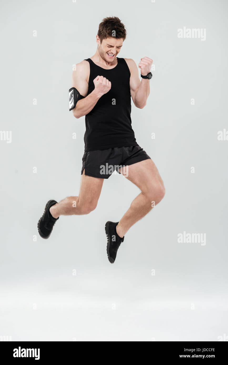 Picture of handsome young sportsman jumping showing winner gesture ...