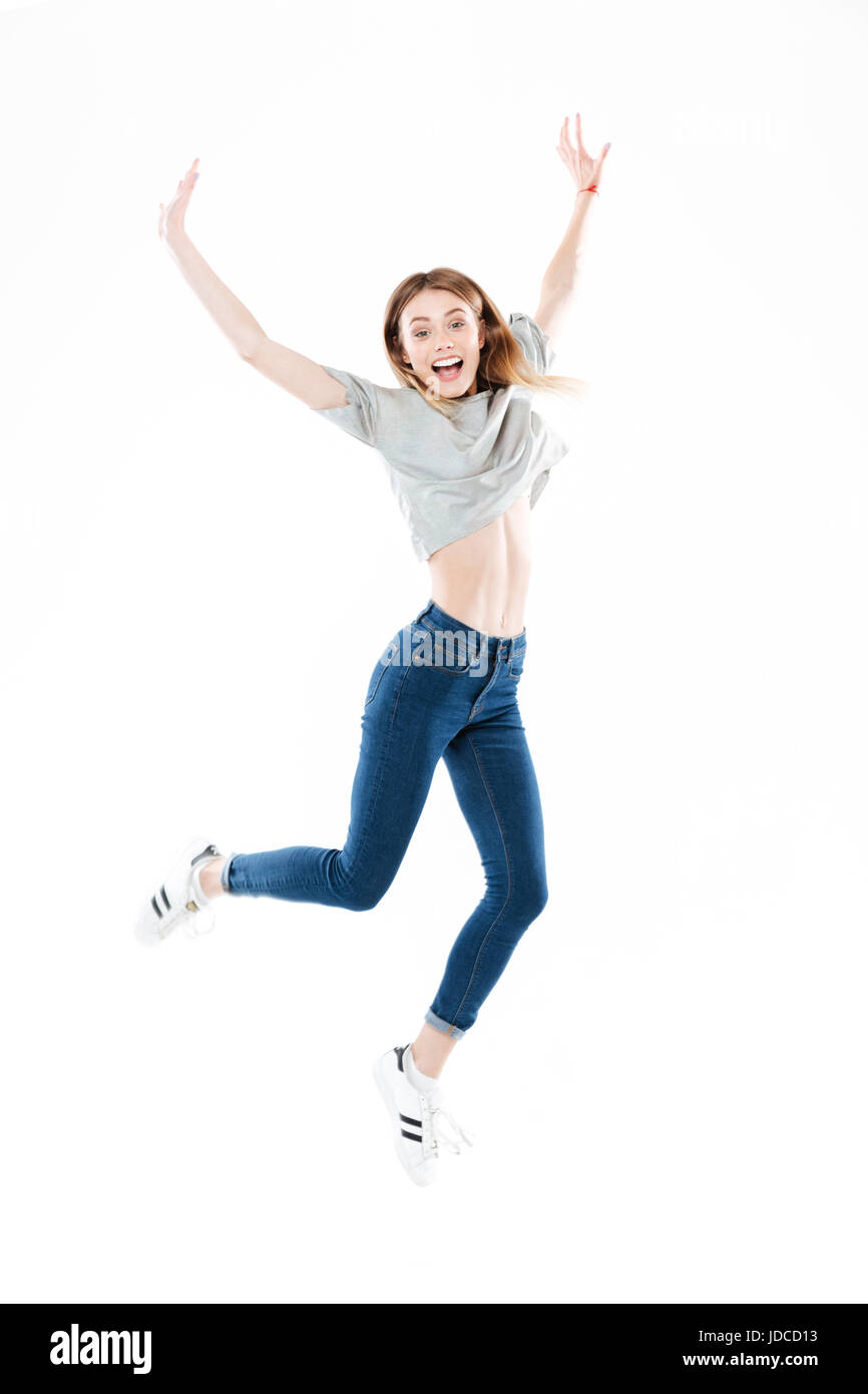 Full length portrait of a happy pretty girl jumping with hands raised ...