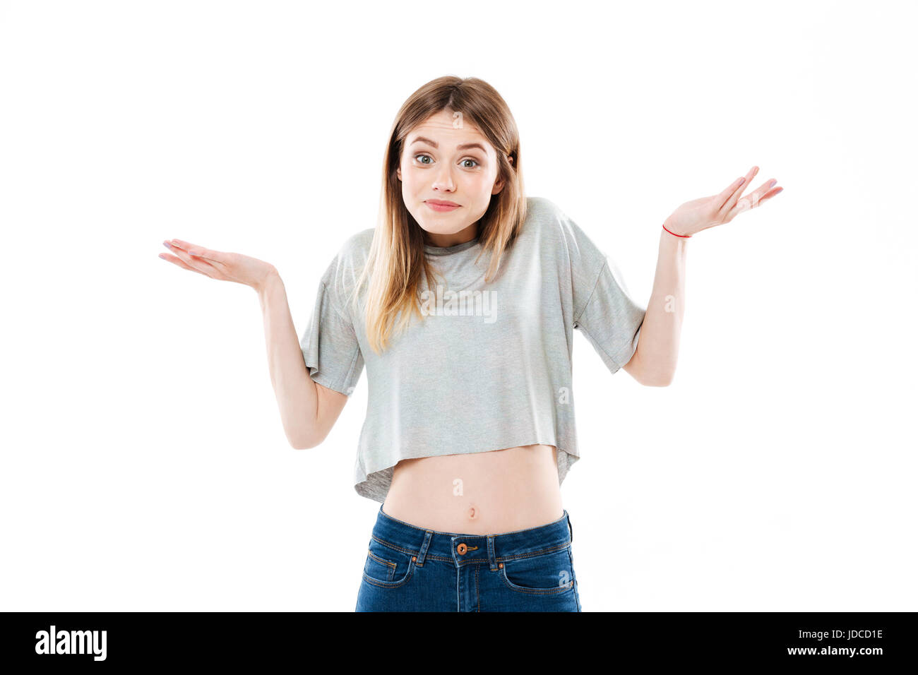 Portrait of a confused pretty girl looking at camera and shrugging ...