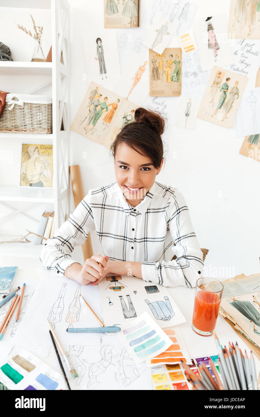 Portrait of a smiling female fashion designer creating sketches at ...