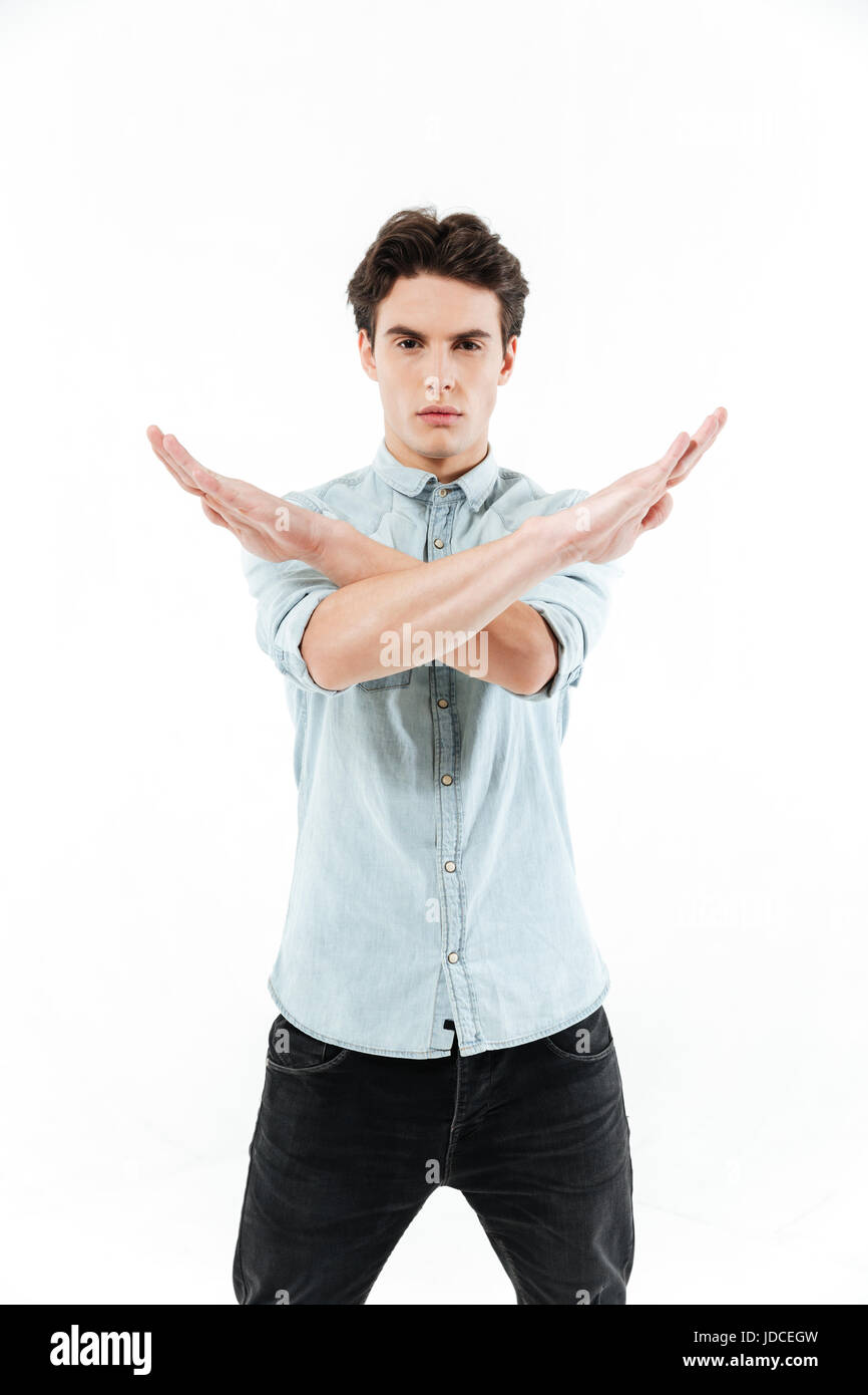 Portrait of a serious confident man standing and showing crossed arms ...
