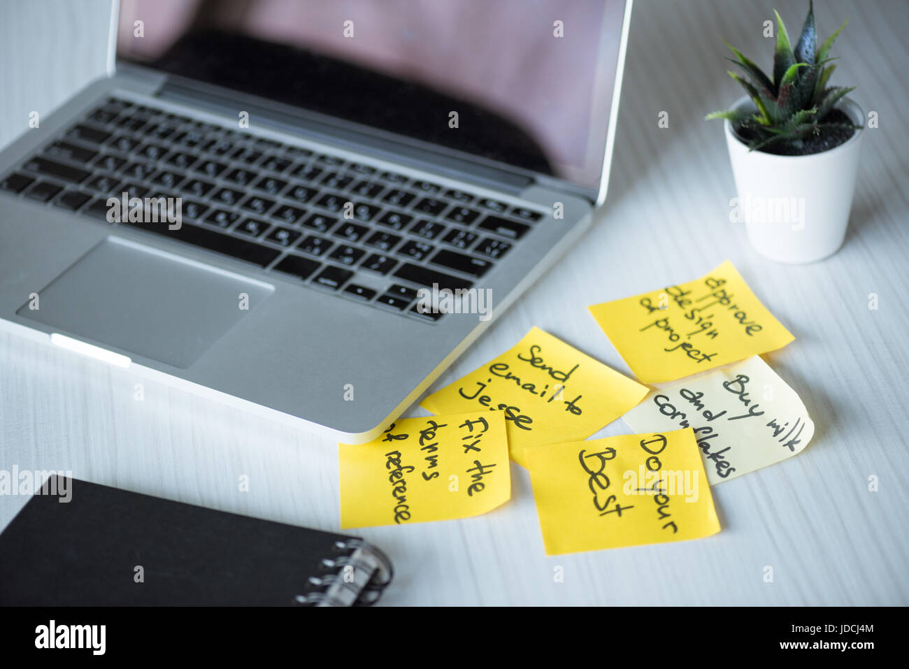 laptop computer, notebook and sticky notes on workplace in empty office ...