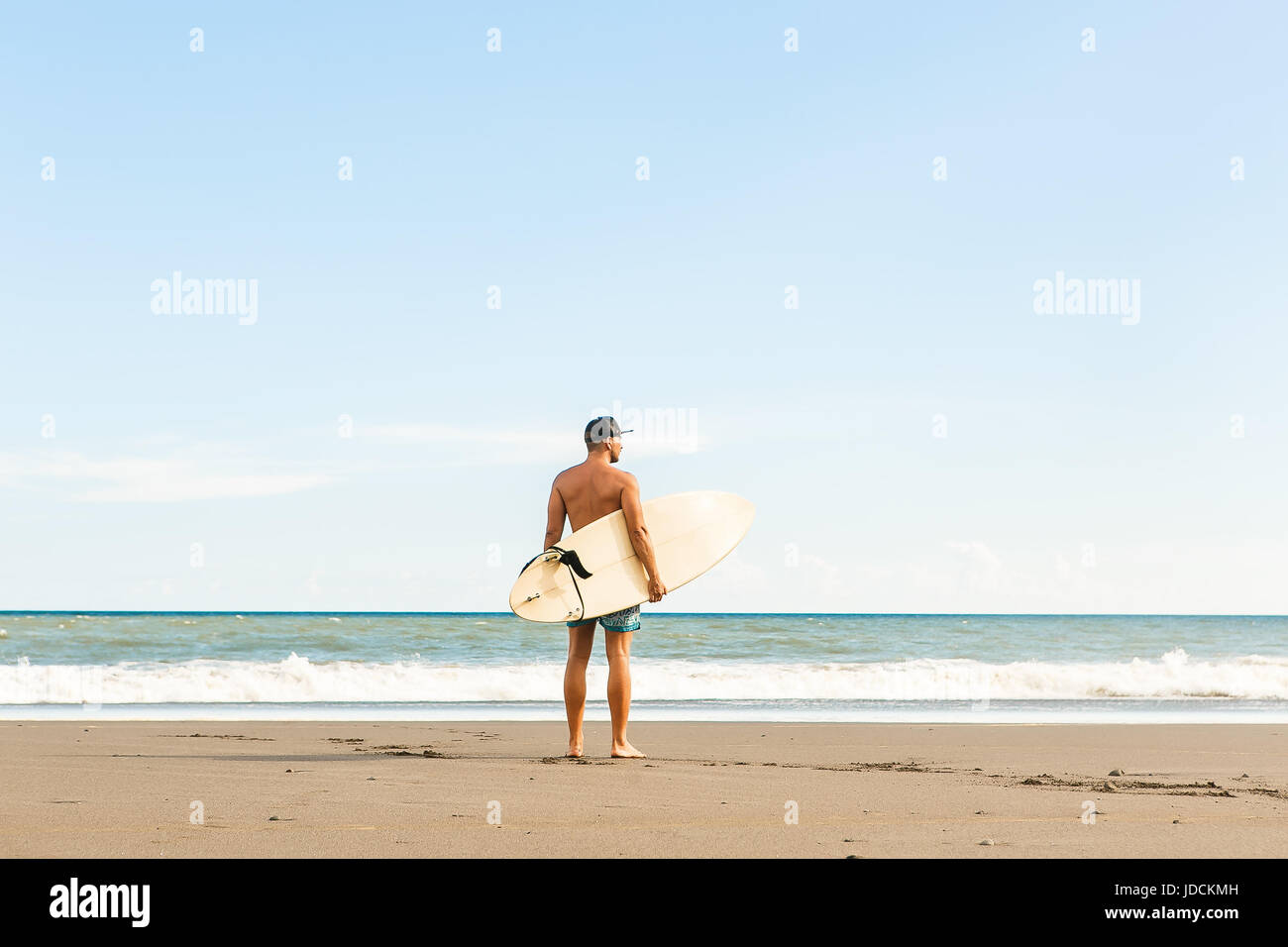 Handsome man stand with long surf surfing board wait on surf spot at ...