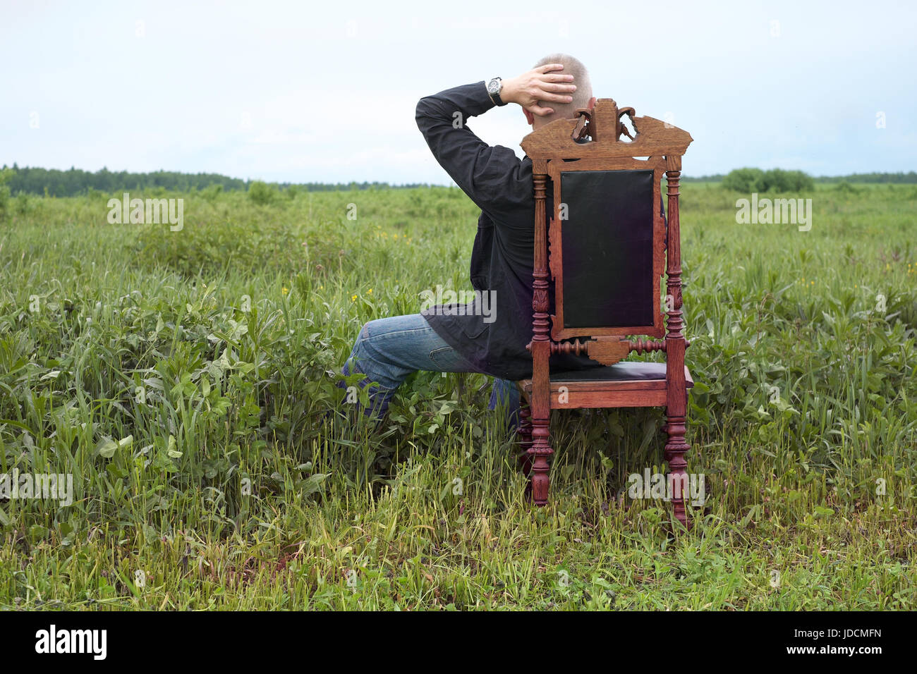 Man having a rest sitting in carved wooden chair, back view outdoor ...
