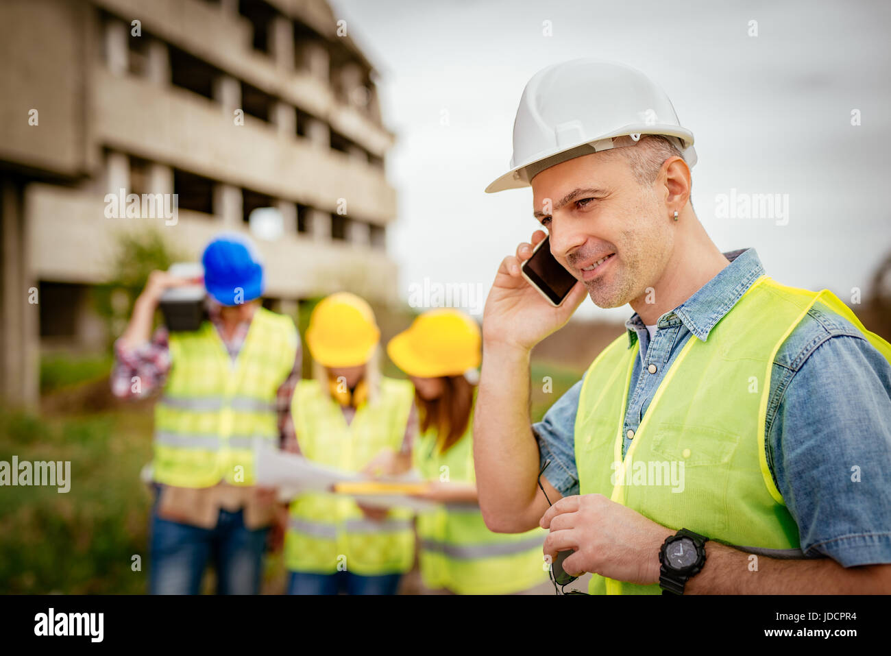 Construction architects using phone in front building damaged in the ...