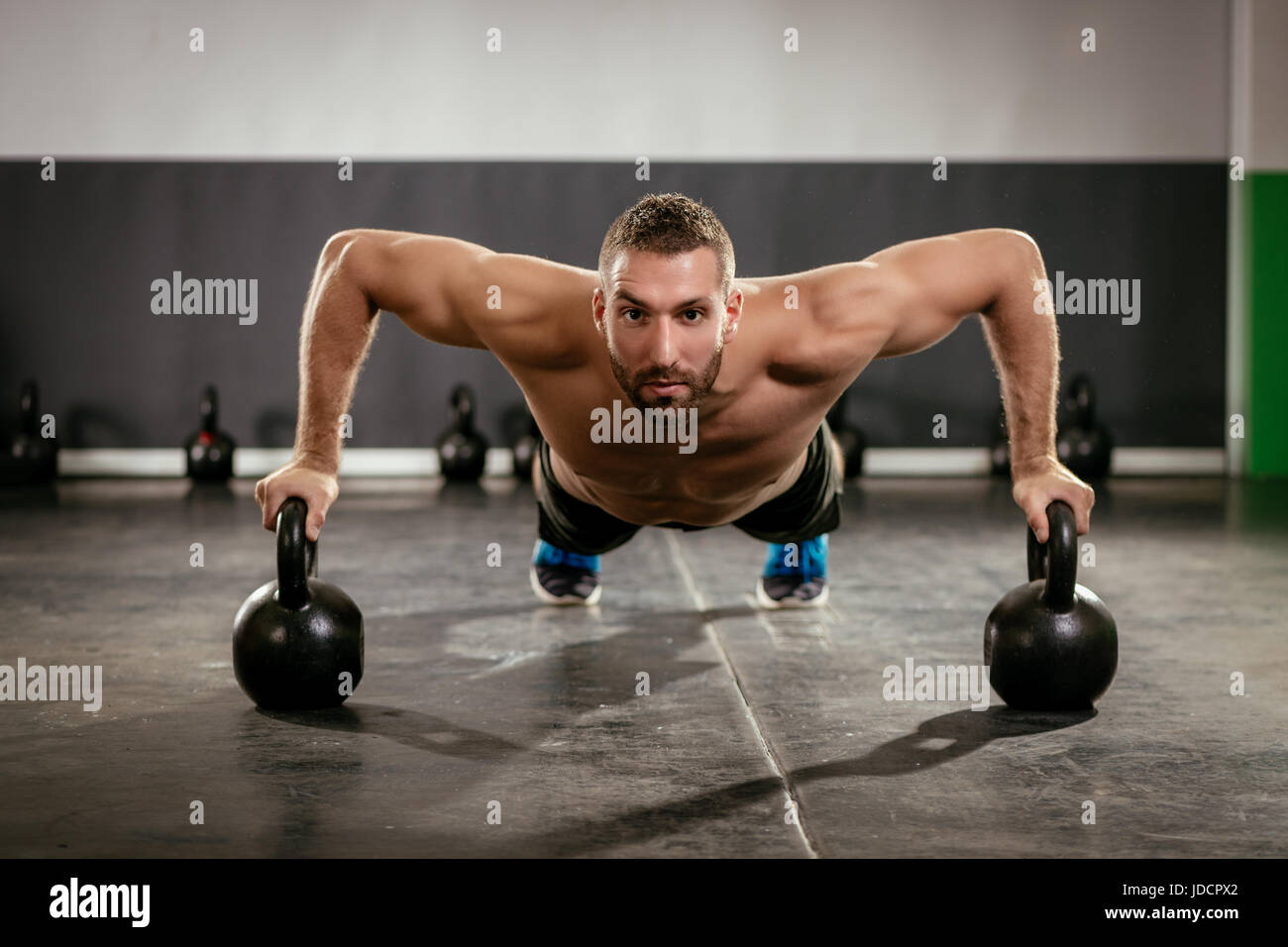 Young muscular man doing push-up exercise with dumbbell. Strong male ...