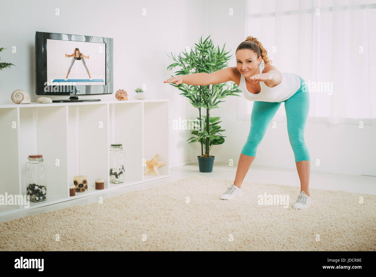 Beautiful young woman doing stretching exercises at home in front of ...