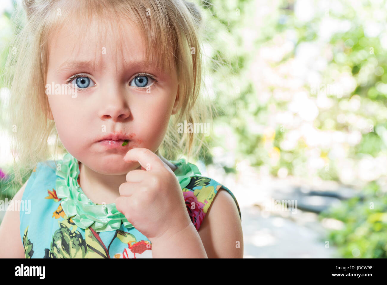 Child, little girl ate a strawberry and smeared her lips, close-up ...