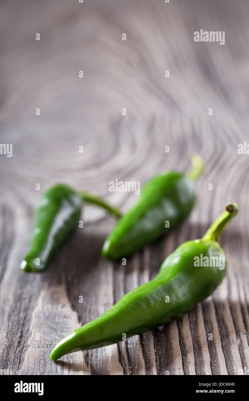 Three green hot peppers on a wooden table. The concept of healthy food ...