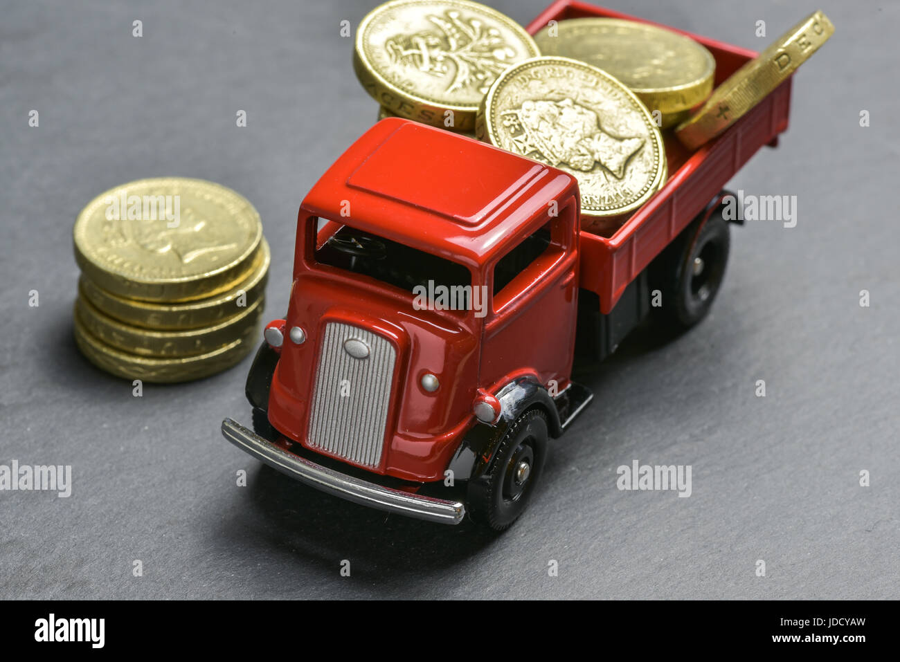 The toy red lorry with coins in a body on a stone background Stock ...