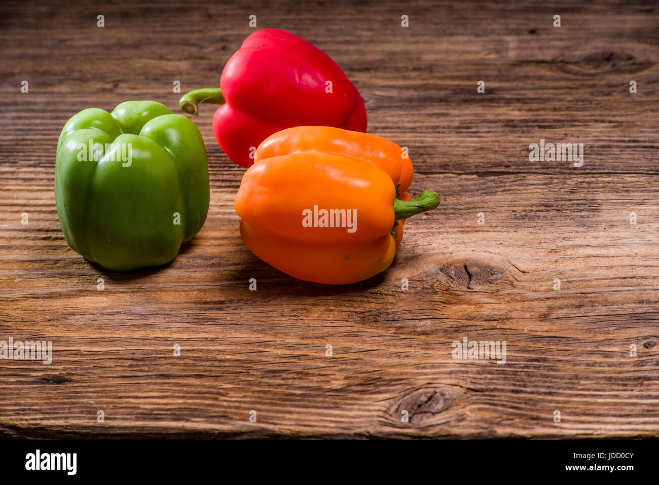 Fresh colorful bell peppers arranged on a rustic table Stock Photo - Alamy