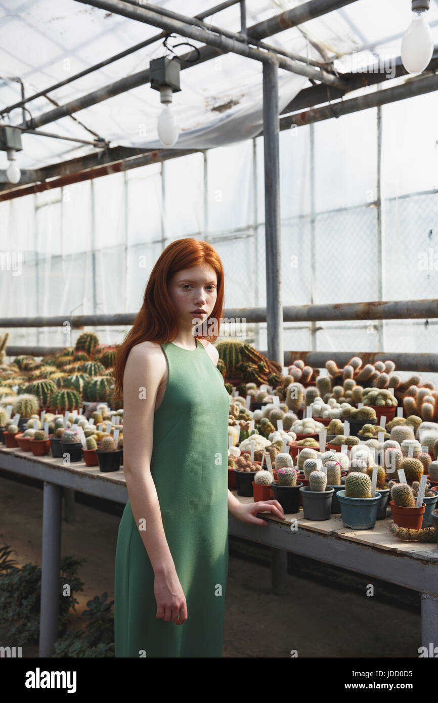 Portrait of a young redheaded girl standing in a glass house and ...