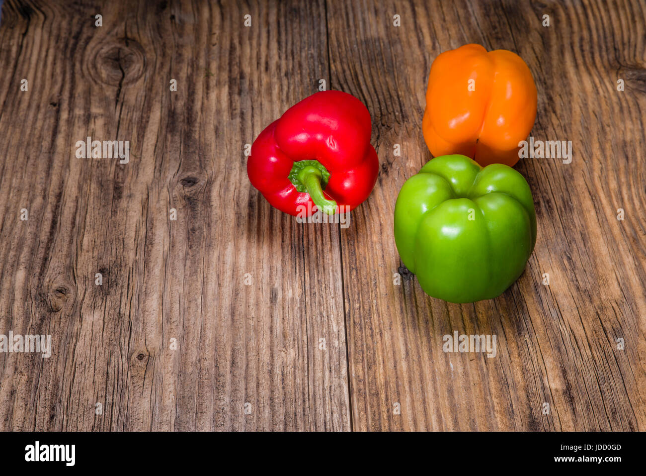 Fresh colorful bell peppers arranged on a rustic table Stock Photo - Alamy