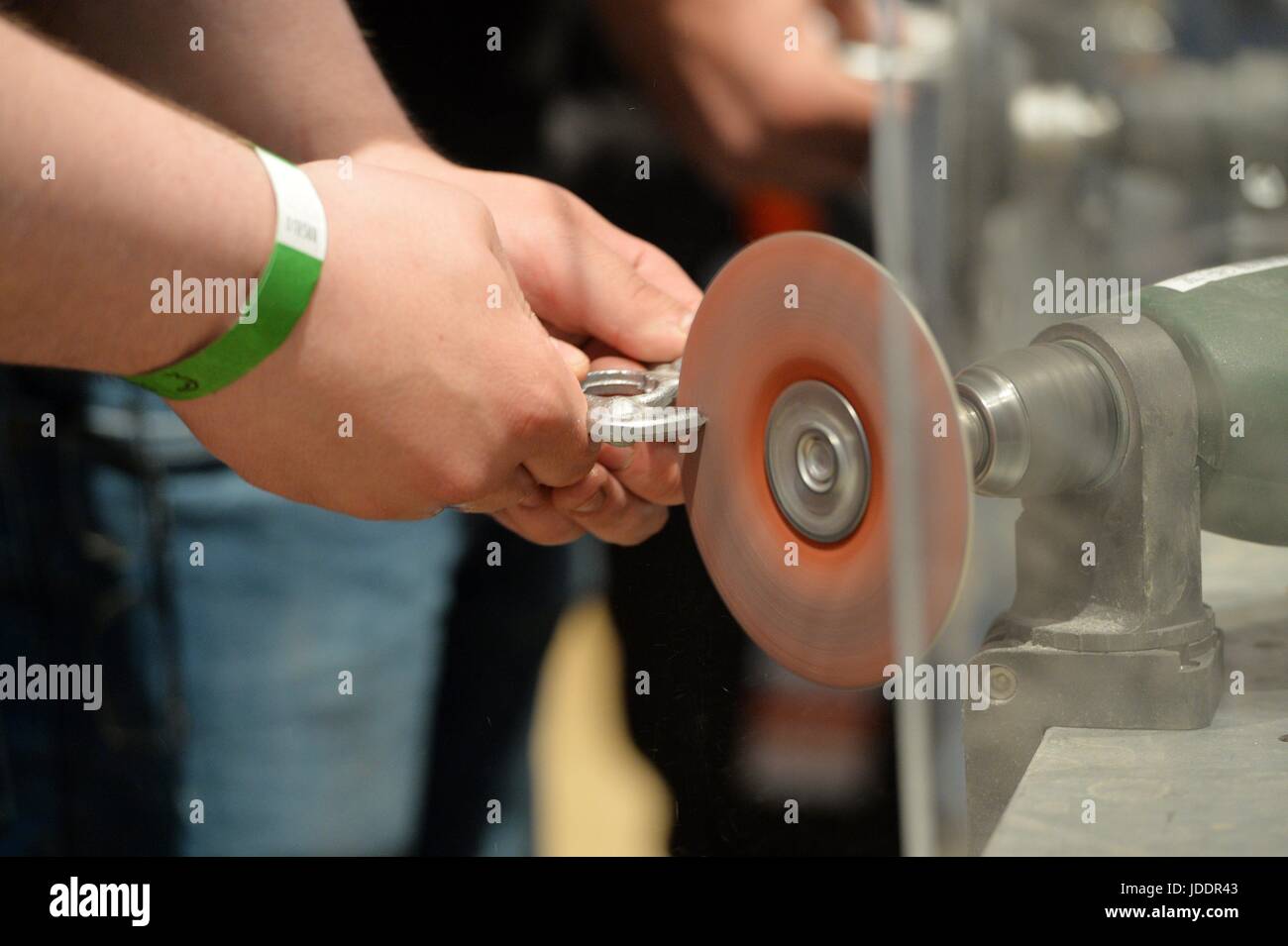 A school boy is sanding a piece of metal at the fair Ideen Expo ...