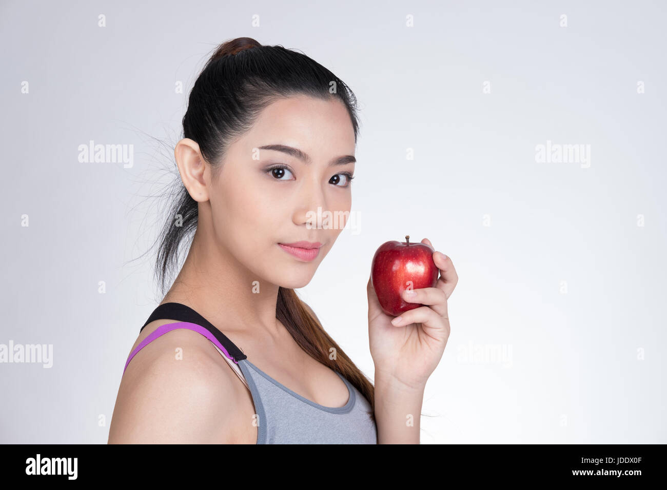 beautiful asian healthy athletic sporty girl with red apple after training. attractive smiling ...