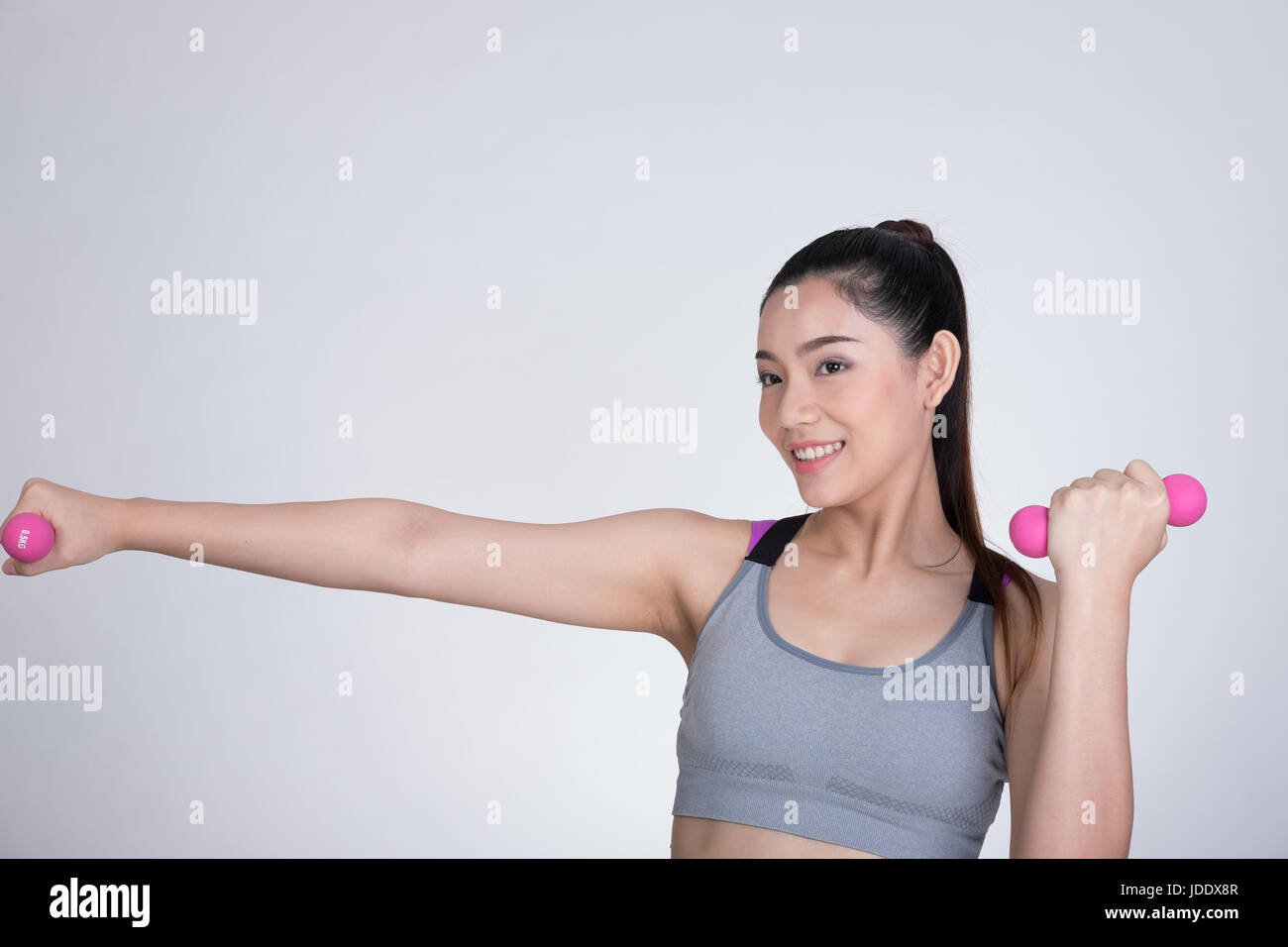 Young beautiful asian sporting woman training with dumbbell. Pretty ...