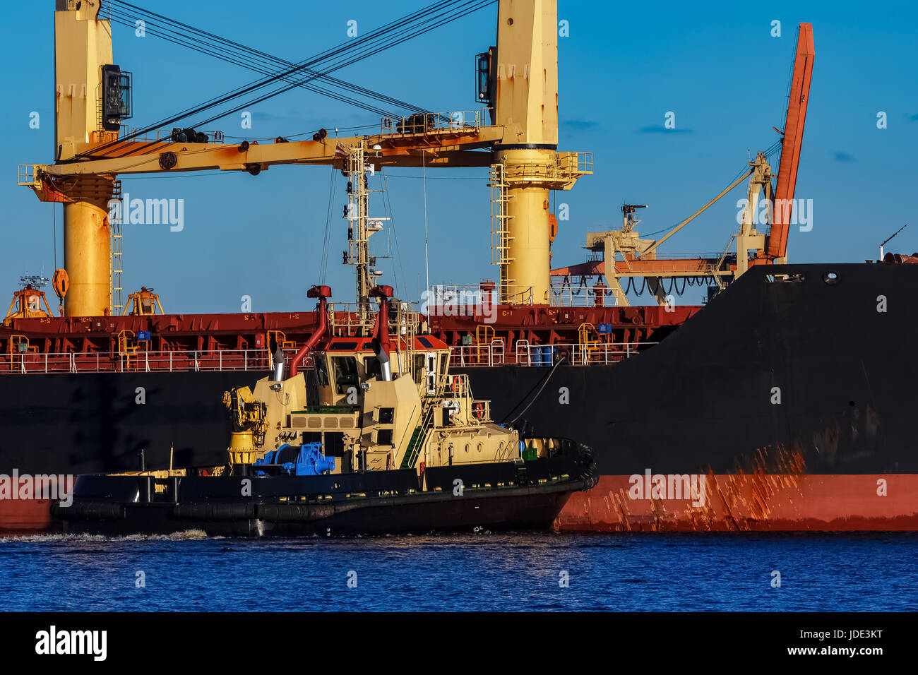 Black cargo ship mooring at the port with tug ship support Stock Photo ...