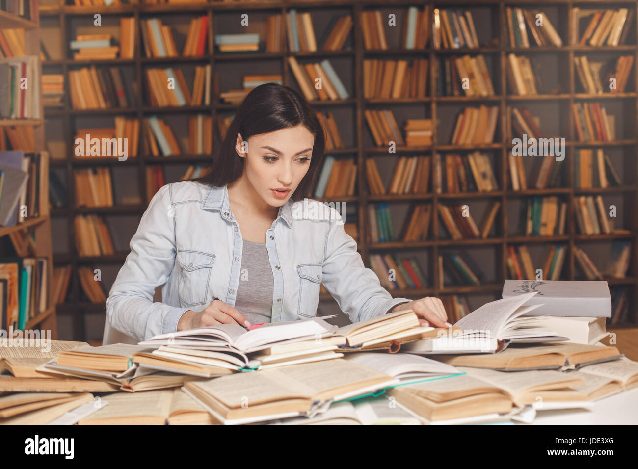 Young female study in the library reading book Stock Photo - Alamy