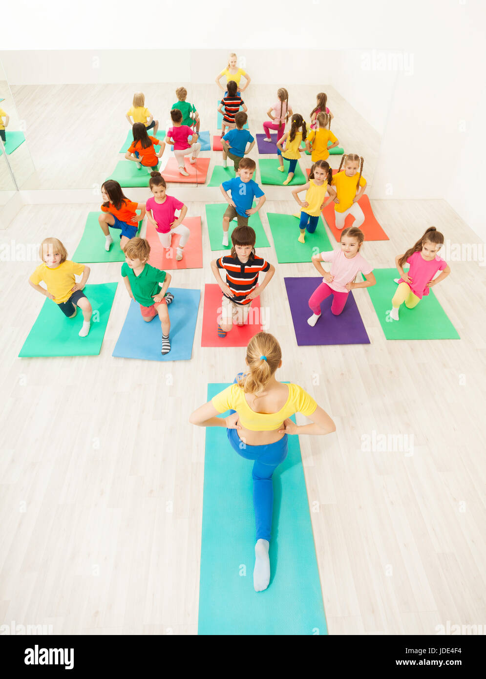 Group of 5-6 years old boys and girls doing knee bending exercises ...
