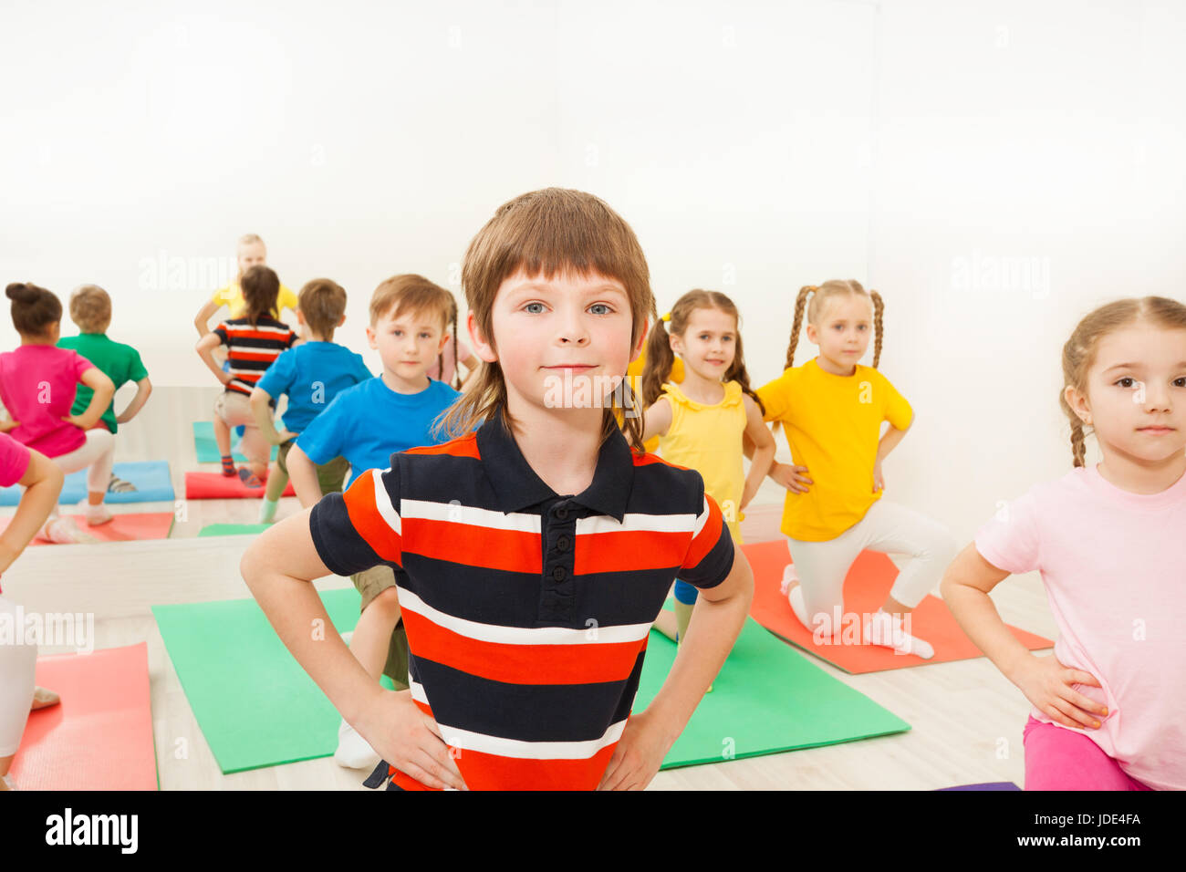 Portrait of Caucasian six years old boy doing kneeling exercises during ...