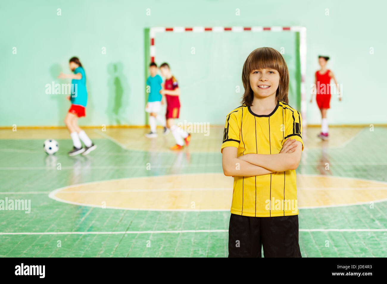 Portrait of happy 12 years old boy, football captain, standing in ...