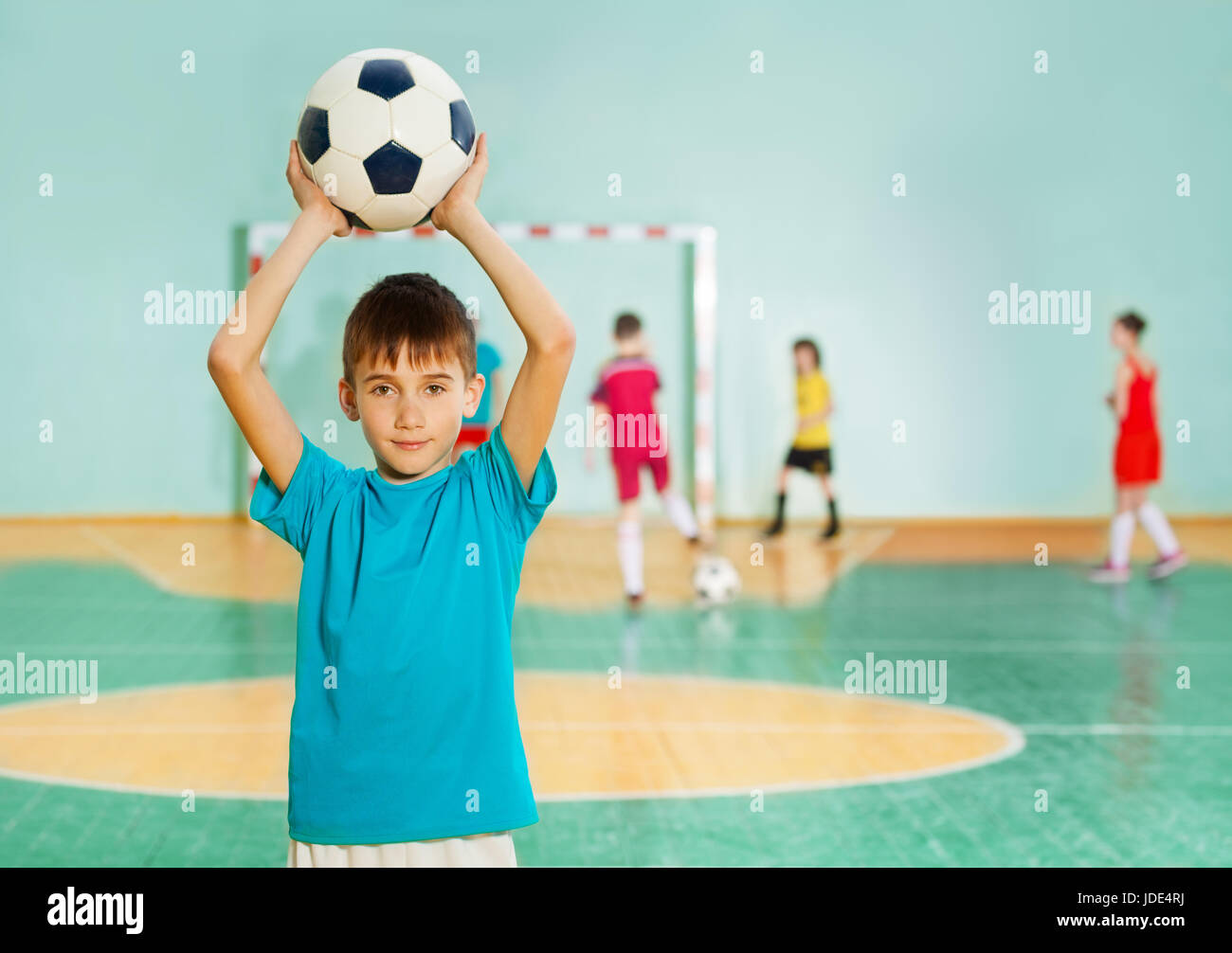 Portrait of 12 years old boy, tossing soccer ball during football match ...