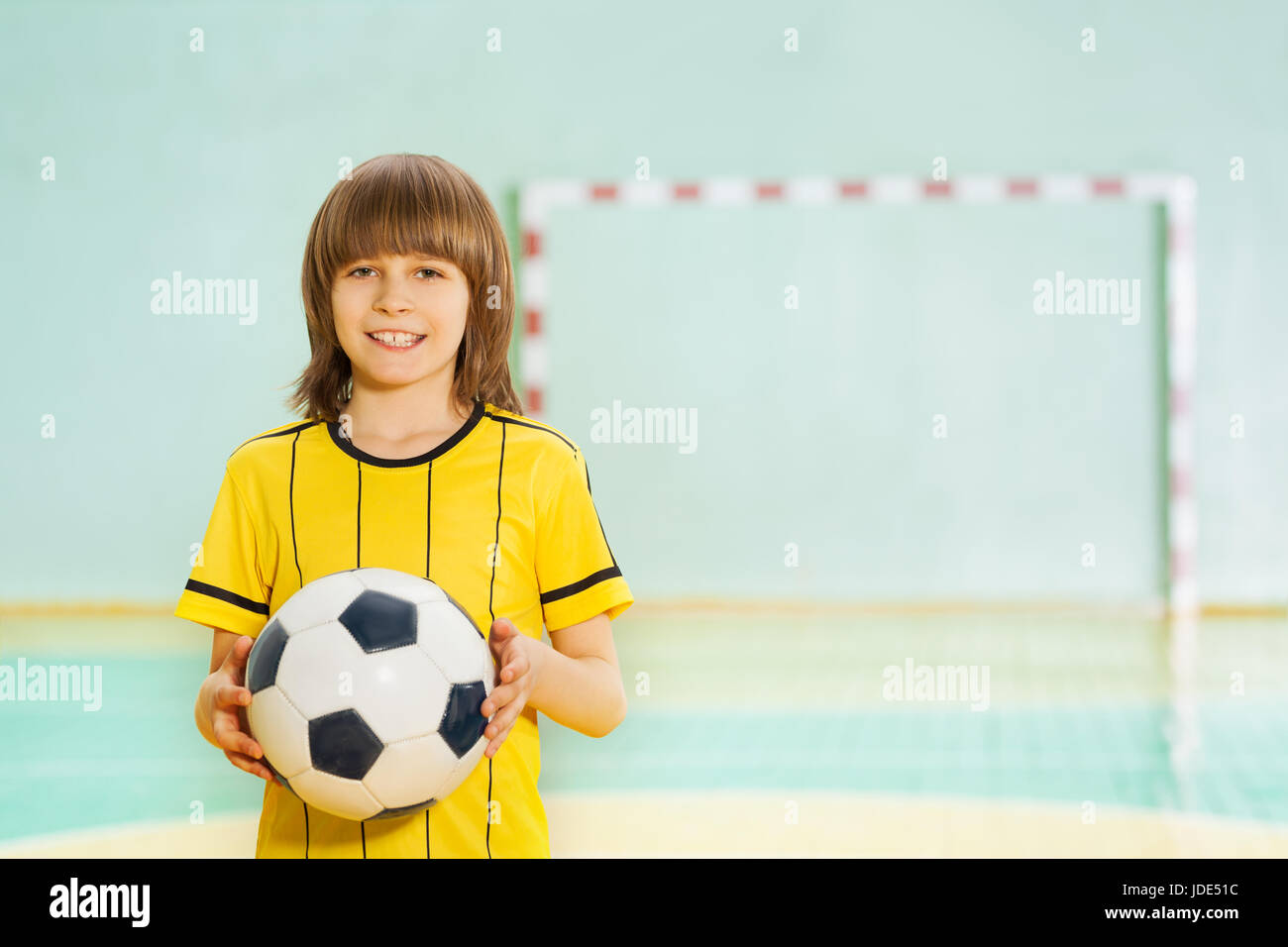 Portrait of smiling 12 years old boy, football player, holding soccer ...
