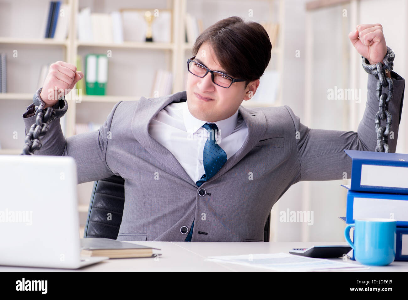 Businessman tied with chains to his work Stock Photo - Alamy