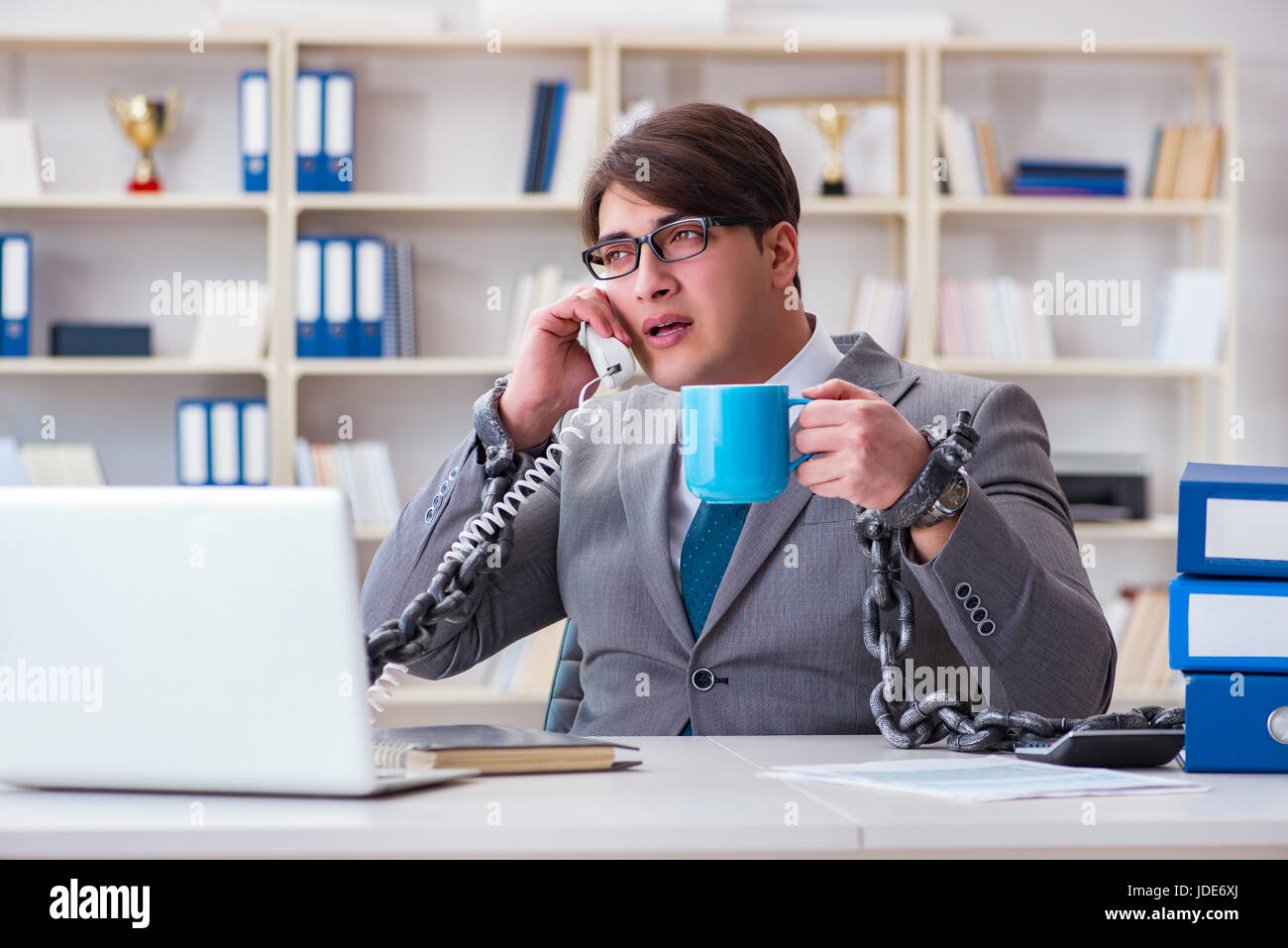 Businessman tied with chains to his work Stock Photo - Alamy